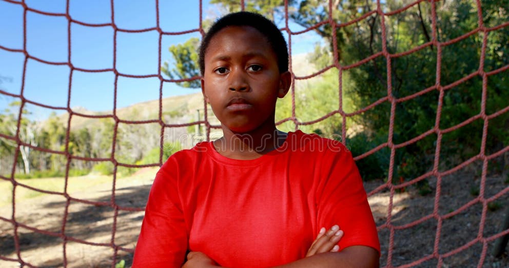 Determined Boy Standing with Arms Crossed Against Net during Obstacle ...