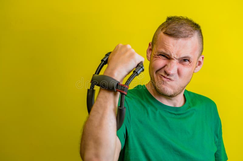 Determined Man Flexing Bicep with Hand Grip Exerciser Against Yellow ...