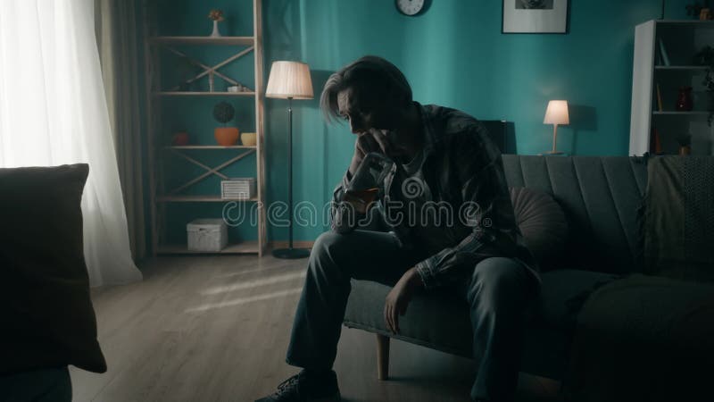 A Devastated Young Man Sits in a Room in the Dark with a Bottle of ...