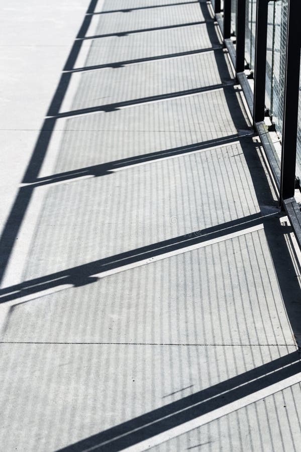 Diagonal Shadows on Cement Walkway from Metal and Glass Panel Barrier ...