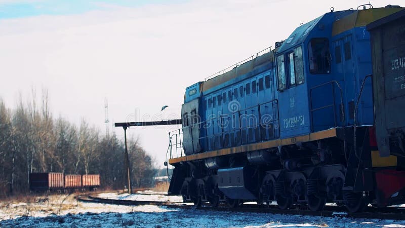 Diesel Locomotive Pulls Wagons with Cargo on a Snow-covered Railway ...