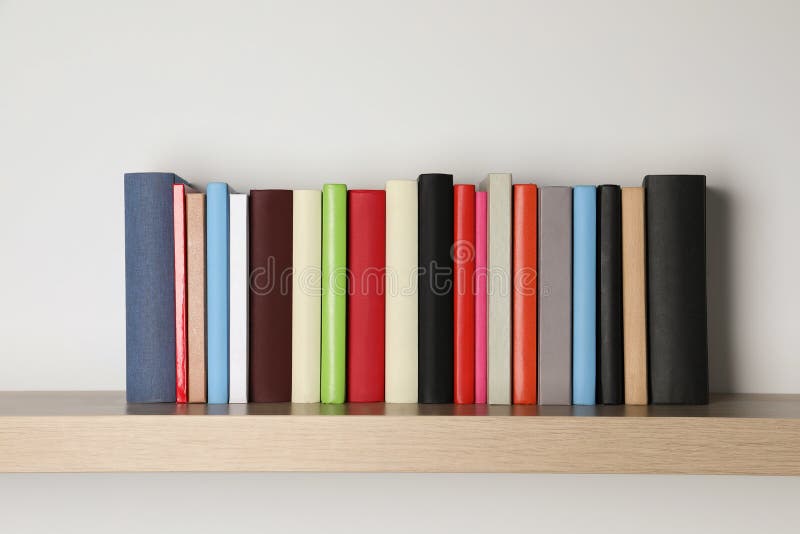 Different Books on Wooden Shelf Near White Wall Stock Photo - Image of ...