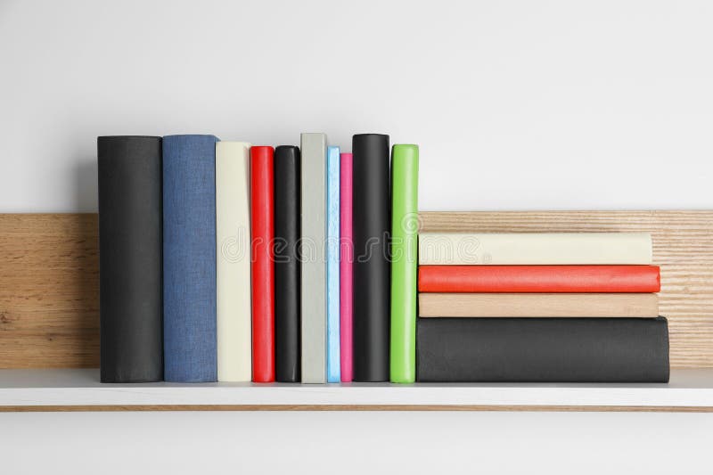 Different Books on Wooden Shelf Near White Wall Stock Photo - Image of ...