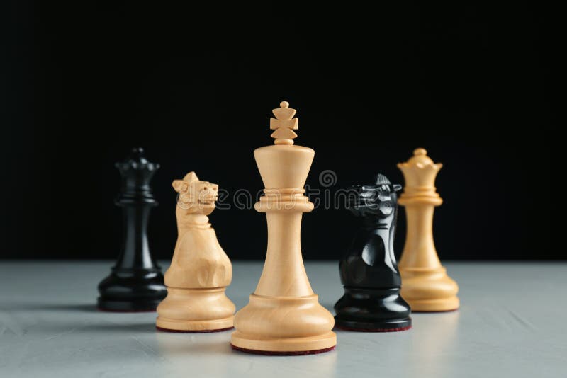 Different Chess Pieces on Grey Table Against Dark Background Stock ...