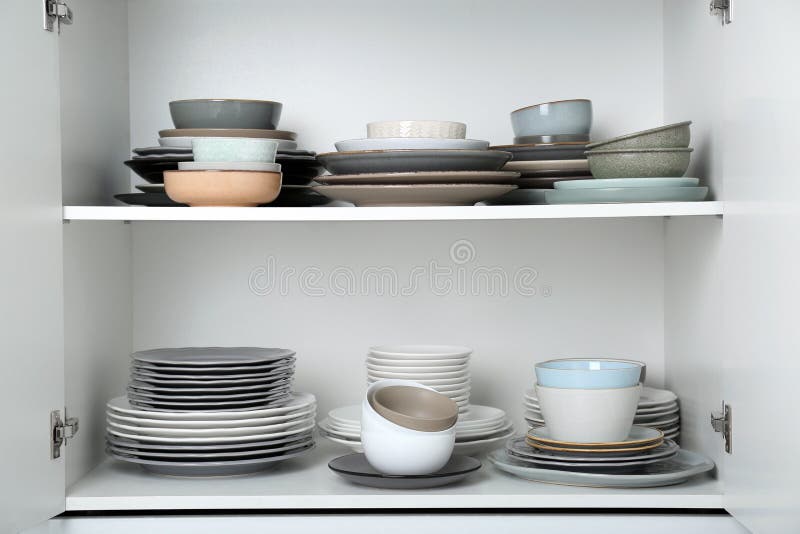 Different Clean Plates and Bowls on Shelves in Cabinet Stock Photo ...