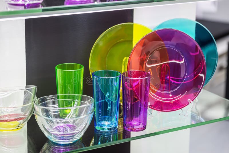 Different-colored Glass Cups, Plates and Saucers are on the Counter ...