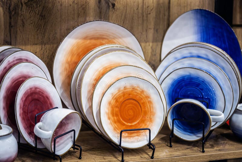 Different-colored Porcelain Cups, Plates and Saucers are on the Counter ...