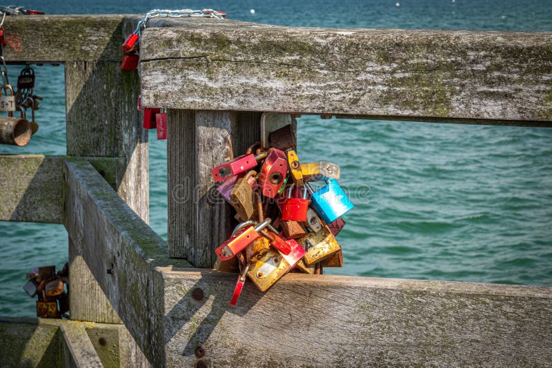 Many Different Coloured Padlocks Hang As a Bundle on a Wooden Railing ...