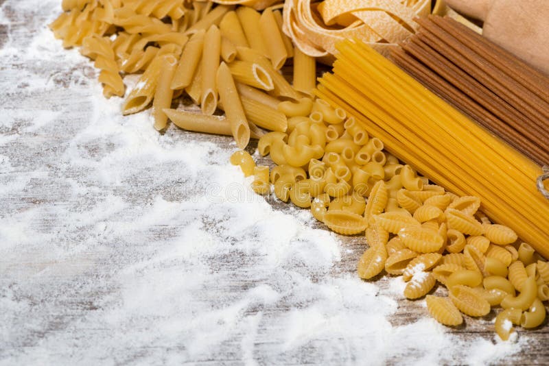 Different Dry Pasta on a Wooden Board with Flour, Top View Stock Photo ...