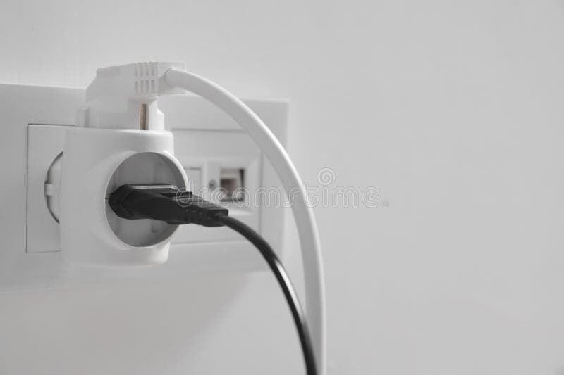 Different Electrical Power Plugs in Socket on Light Wall, Closeup ...