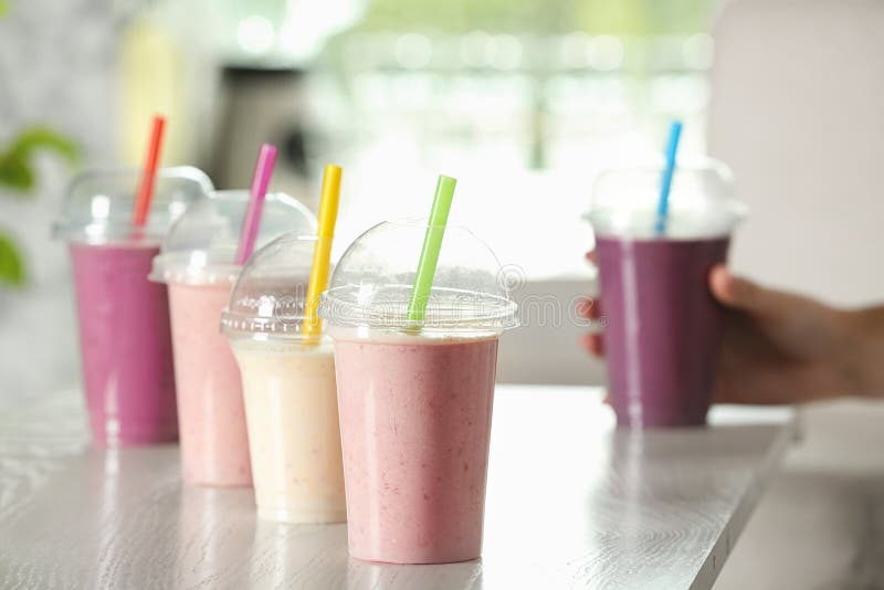 Different Milk Shakes in Plastic Cups on White Wooden Table Stock Image ...