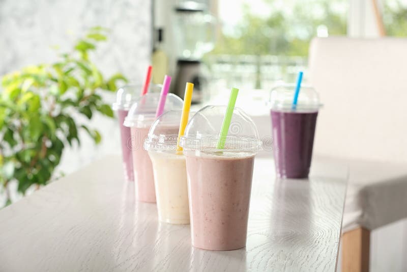 Different Milk Shakes in Plastic Cups on White Wooden Table Stock Photo ...