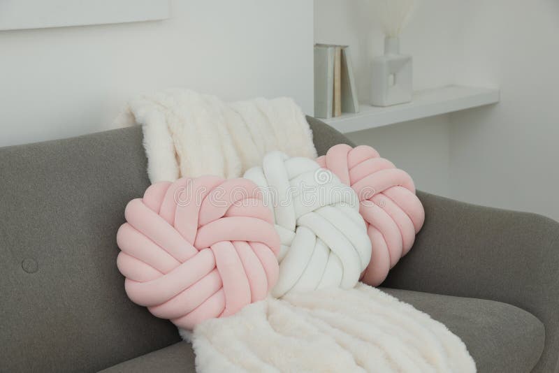 Different Soft Pillows in Shape of Knot and Blanket on Sofa in Room ...