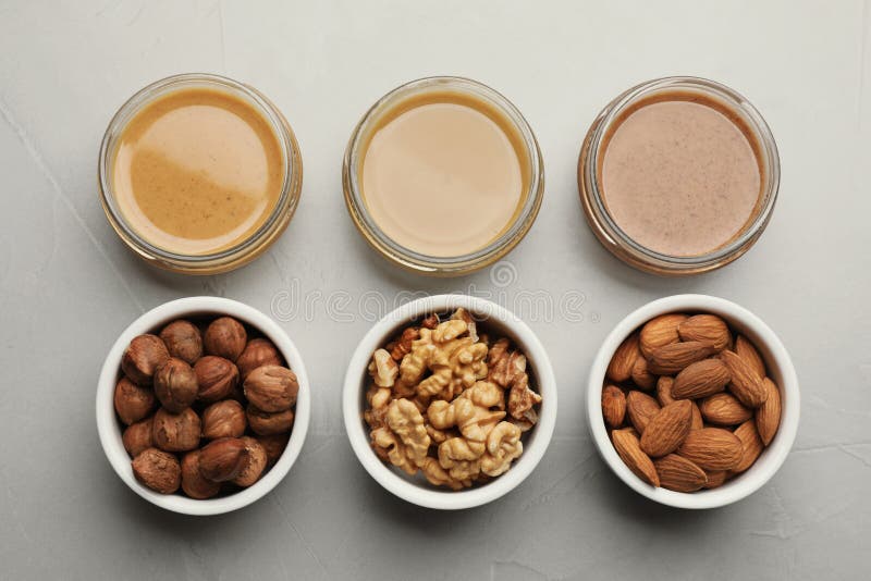 Different Types of Delicious Nut Butters and Ingredients on Grey Table ...
