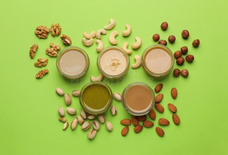Different Types Of Delicious Nut Butters And Ingredients On Light Green Background Flat Lay