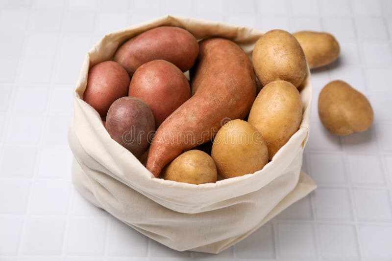 Different Types of Fresh Potatoes in Bag on White Table Stock Photo ...