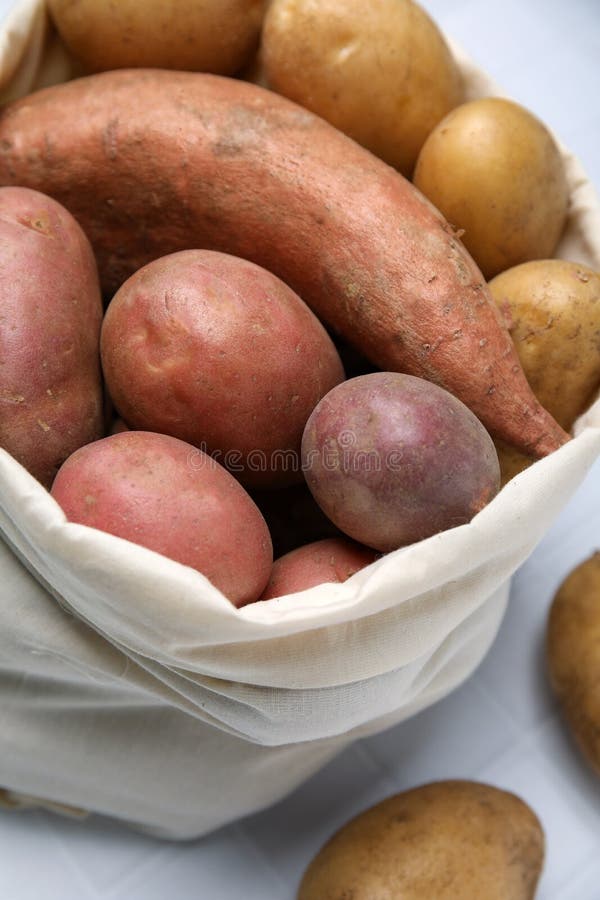 Different Types of Fresh Potatoes in Bag on White Table, Closeup Stock ...