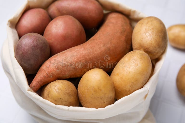 Different Types of Fresh Potatoes in Bag on White Table, Closeup Stock ...
