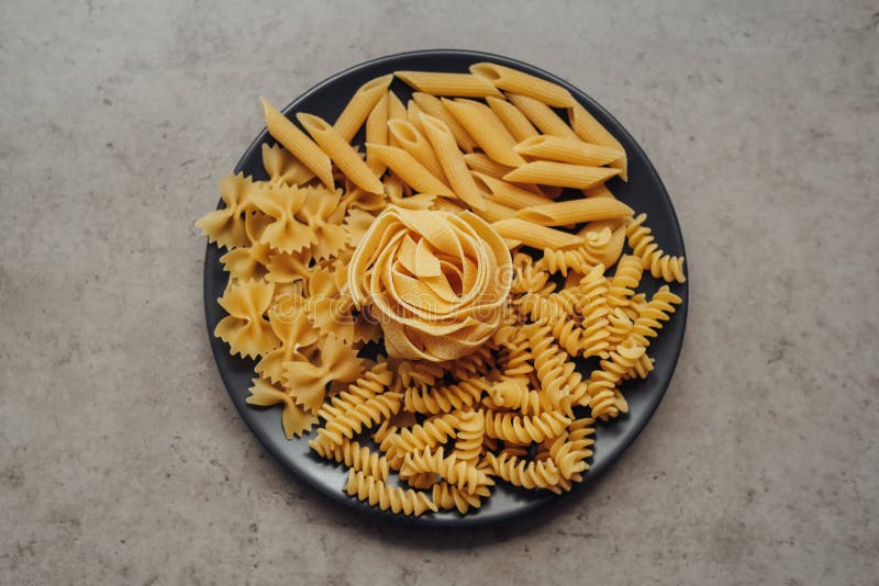 Different Types of Pasta Laid Up on the Black Plate on the Table Stock ...