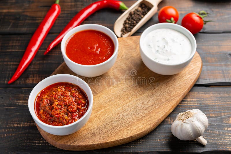 Different Types of Sauces in Bowls on a Cutting Board with Garlic. on ...