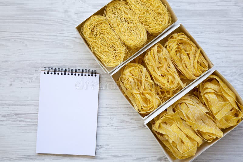 Different Uncooked Pasta in Paper Boxes with Notepad on White Wooden ...