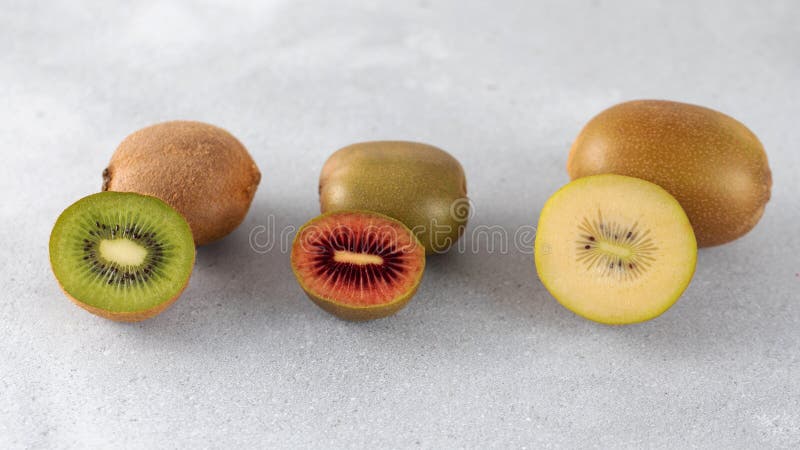 Different Varieties of Kiwi Lie in a Pile on the Table. Halves of Red ...