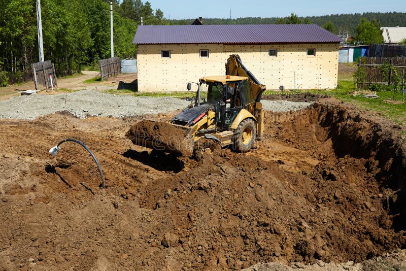 A Digger Operates in a Rural Setting, Carefully Digging a Deep ...