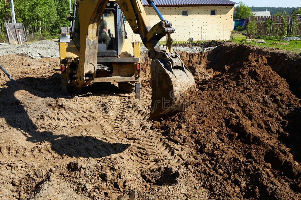 A Digger Operates in a Rural Setting, Carefully Digging a Deep ...