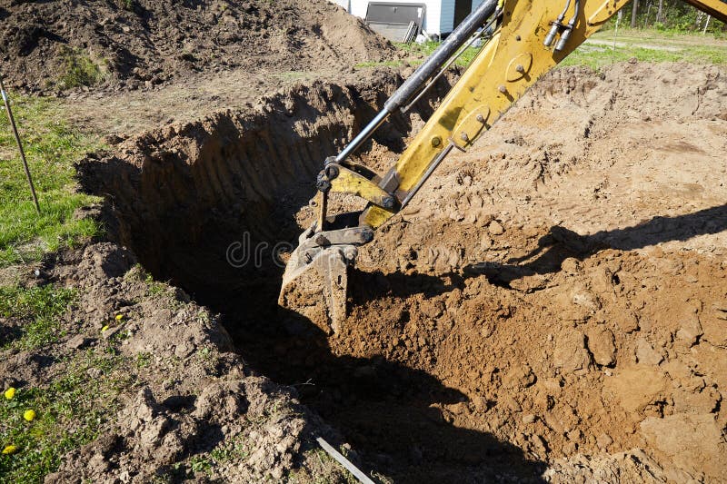 A Digger Operates in a Rural Setting, Carefully Excavating a Deep ...