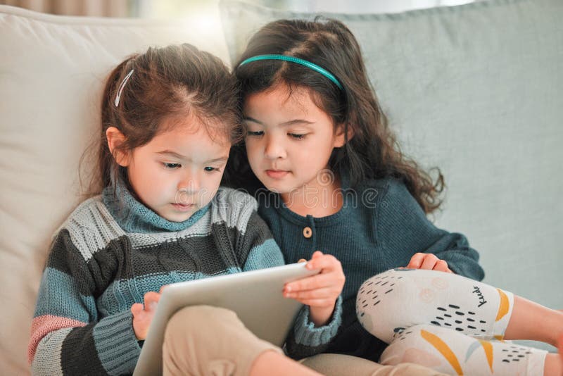 A Digital Babysitter. Two Young Sisters Using a Digital Tablet Together ...