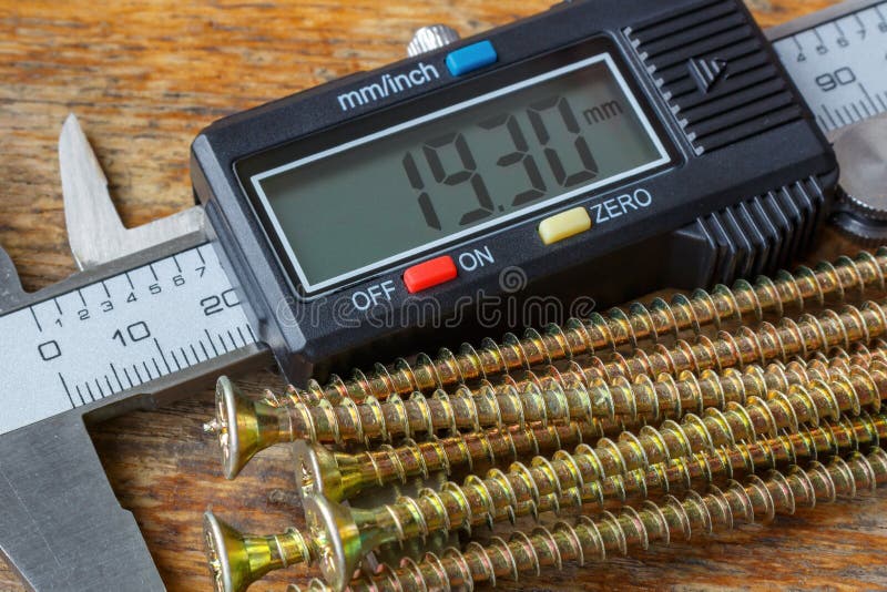 Digital Electronic Caliper with Yellow Long Screws on Wooden Table in ...