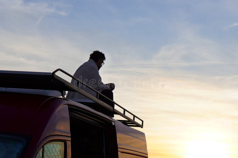 Digital Nomad, Camper Van. Man Sitting on the Roof of His Camper Van, Drinking Coffee at Sunset ...