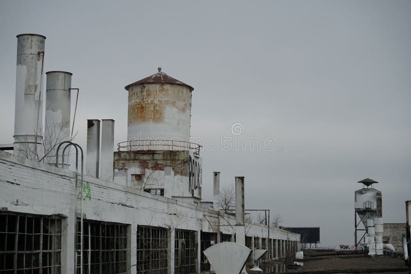 A Dilapidated Building with Chimneys, and Water Tower in the Distance ...