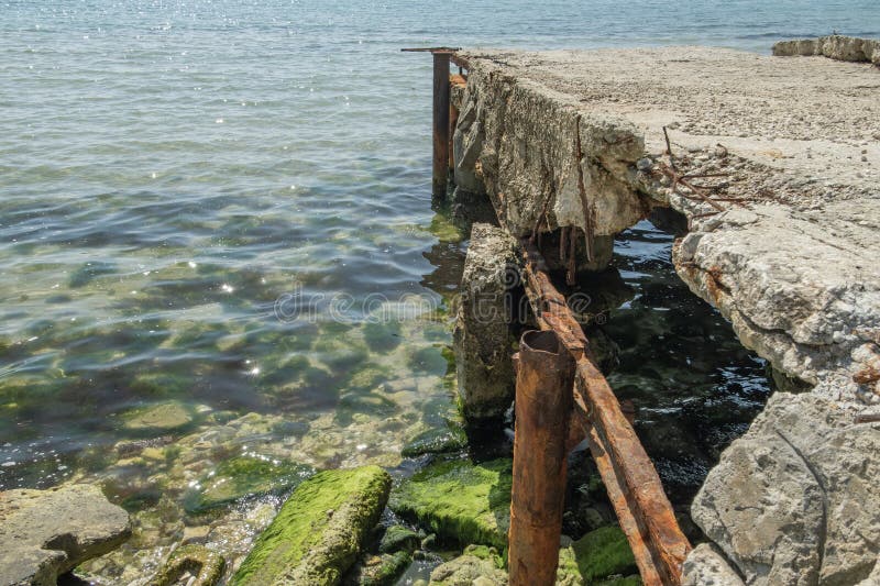 Dilapidated Concrete Structure Extends into the Clear, Green-tinted Sea ...