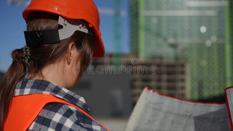A Construction Worker is Meticulously Reviewing Blueprints at a Bustling Job Site Today Stock ...