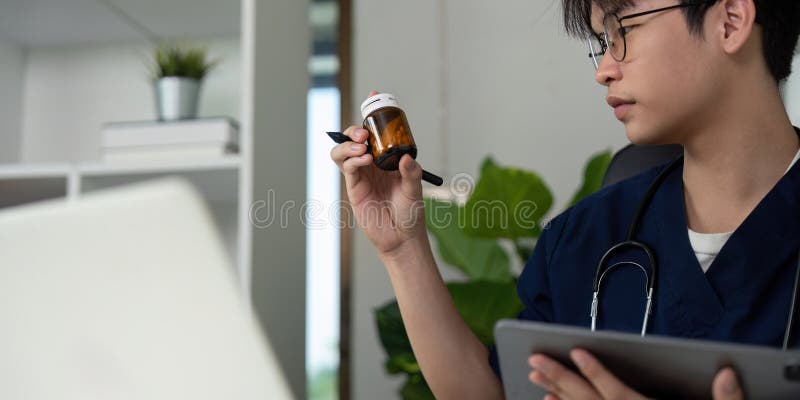 Medical Student Examining Medication while Taking Notes in a ...