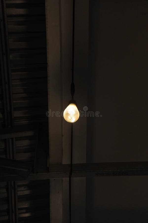 Dimly Lit Incandescent Light Bulb Hanging in an Industrial Setting ...