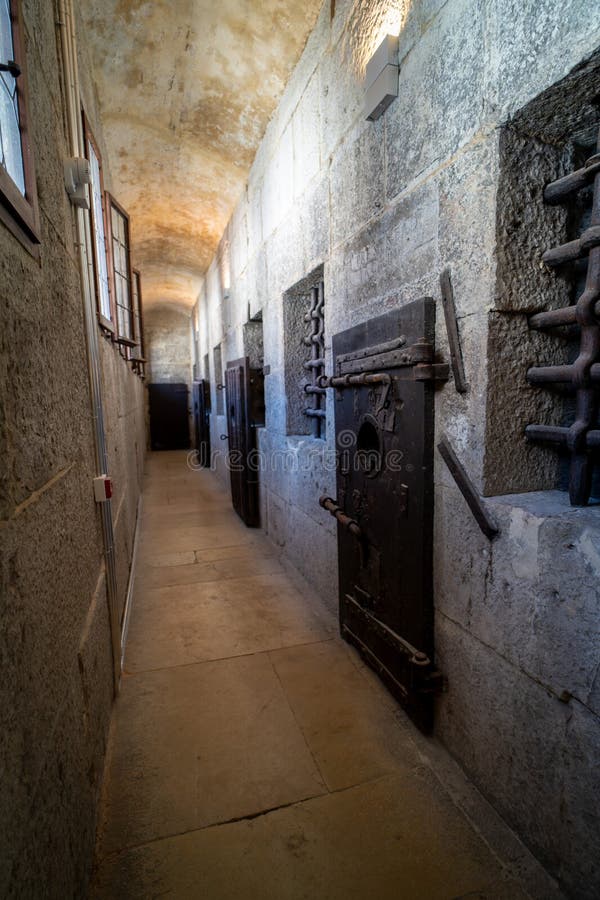 Dimly Lit Stone Prison Corridor with Iron Doors Stock Photo - Image of ...