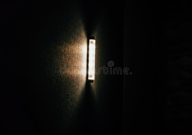 Dimly Lit Vertical Wall Light Fixture in a Dark Room Stock Photo ...