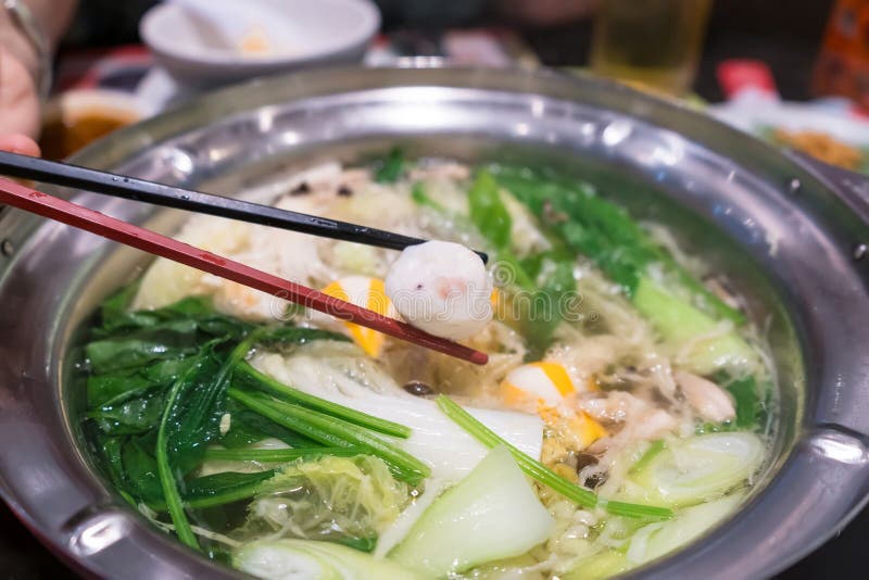 Diners Enjoying a Hot Pot Filled with Vegetables and Meatballs Stock ...