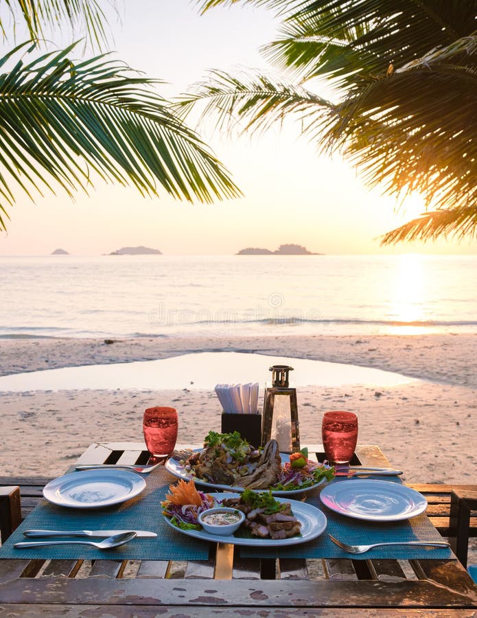 Dinner Table during Sunset on a Beach with Fish and Thai Food Stock ...