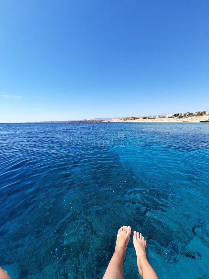 Dipping Feet in Crystal Clear Ocean Water with a Distant Beach Under a ...