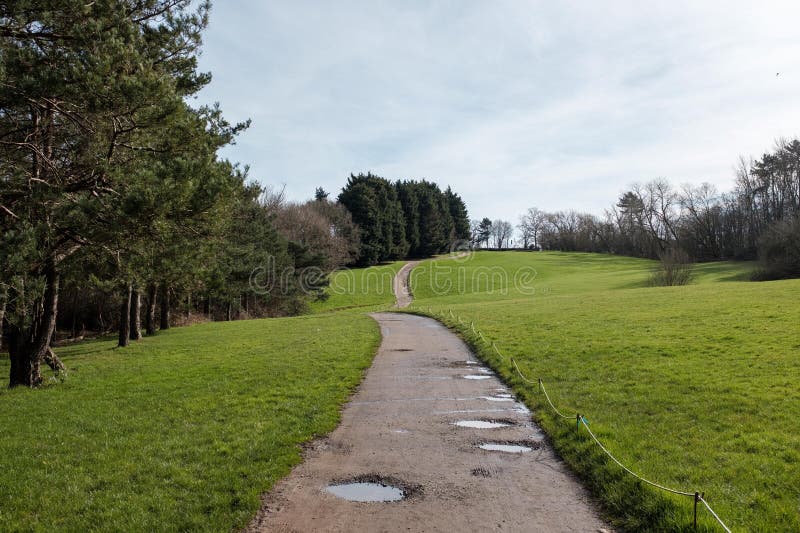 Dirt Path with Shallow Puddles Winds through a Grassy Field. Trent Park ...