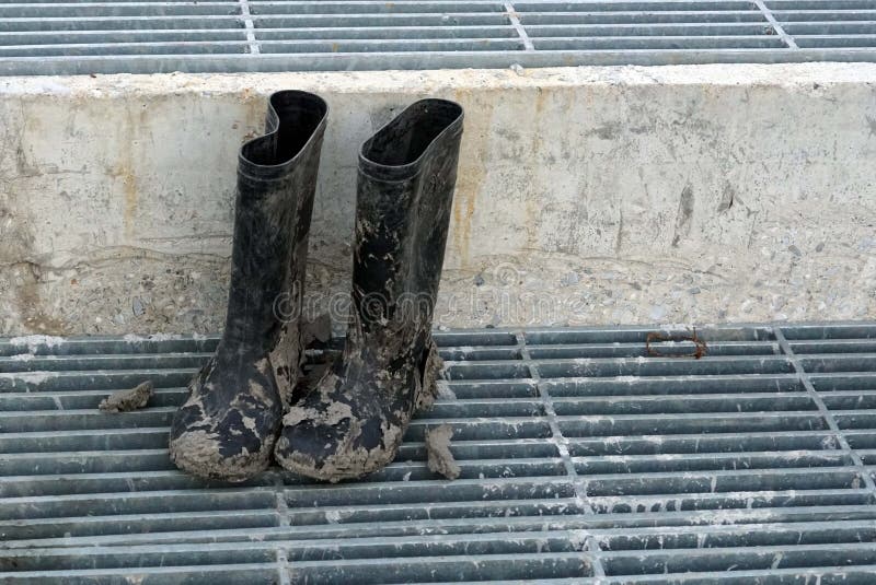 A Dirty Black Rubber Boots on Grille of a Drain Pipe in a Construction ...