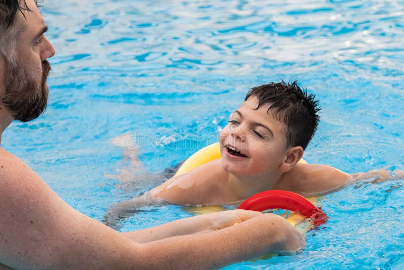 Disabled Boy with a Float Laughs As he Plays and Swims in a Pool with ...