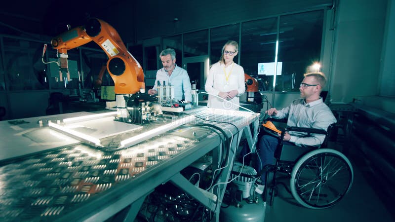 A Disabled Engineer and His Colleagues are Observing a Robotic Arm ...