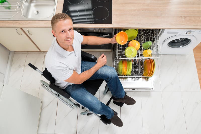 Man On Wheelchair Putting Laundry Into The Washing Machine Stock Photo ...