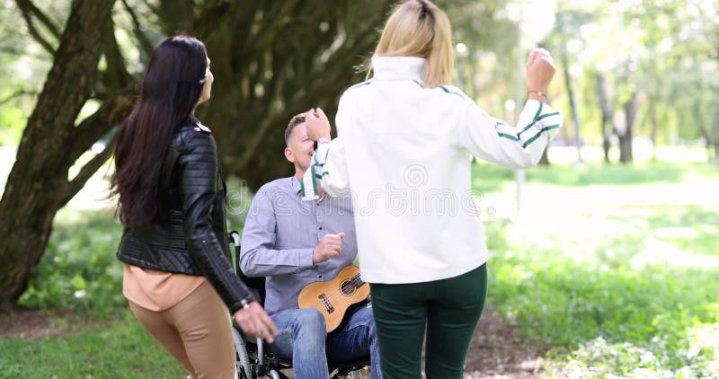 Disabled Man Plays Guitar in Park Two Women Dance Stock Video - Video ...