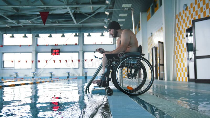 Disabled Man in a Wheelchair Putting on a Swimming Cap and a Goggles ...