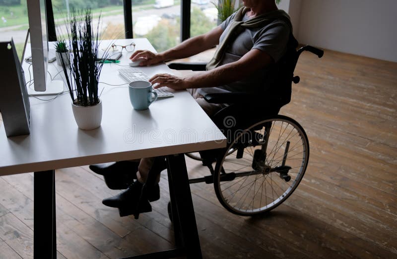 Disabled Man Sitting in Wheelchair at the Table in Front of Computer ...